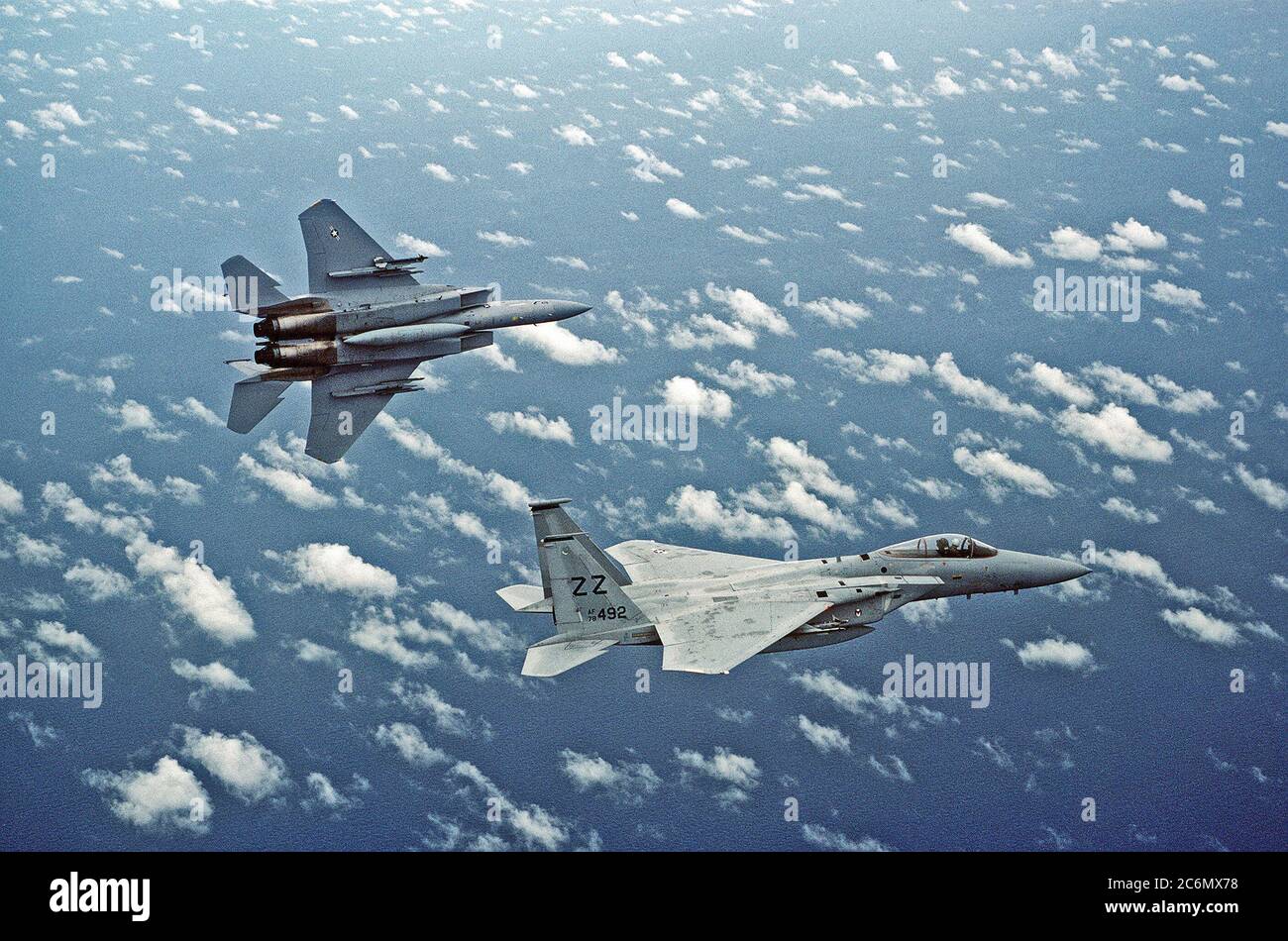 An air-to-air right side view of two F-15 Eagle aircraft. The F-15 in ...