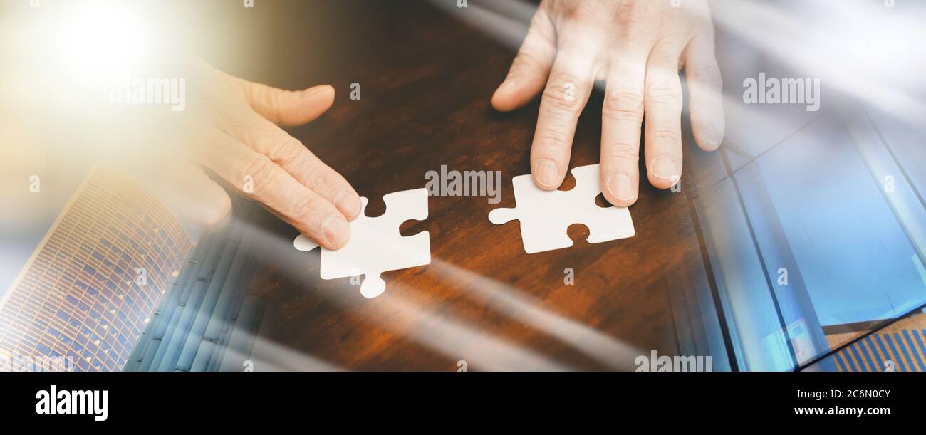 Hands joining two puzzle pieces, teamwork concept; multiple exposure ...