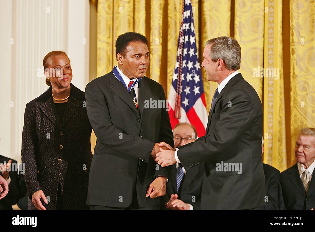 As Mrs. Lonnie Ali looks on, President George W. Bush shakes hands with ...