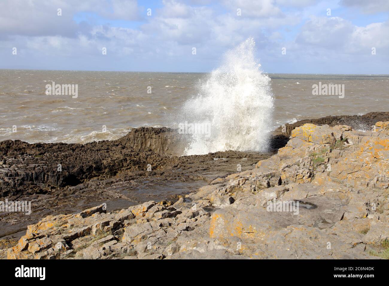A heavy water surge rushes into a narrowing cleft in a rock face ...