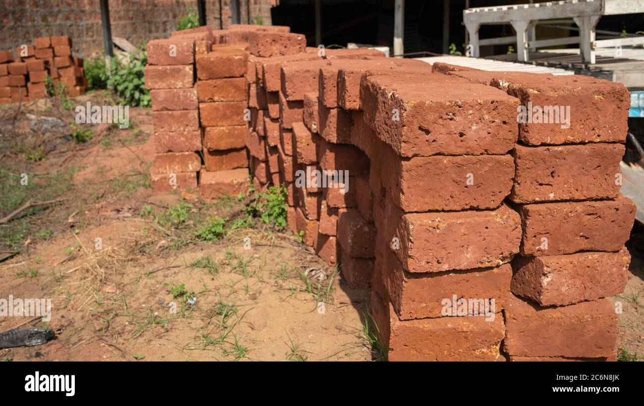 Stacks of bricks in yard. Shabby red bricks stacked on sandy ground ...