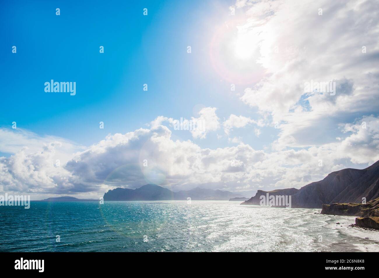 Sandy beach with mountains on background. Mountains are covered with ...