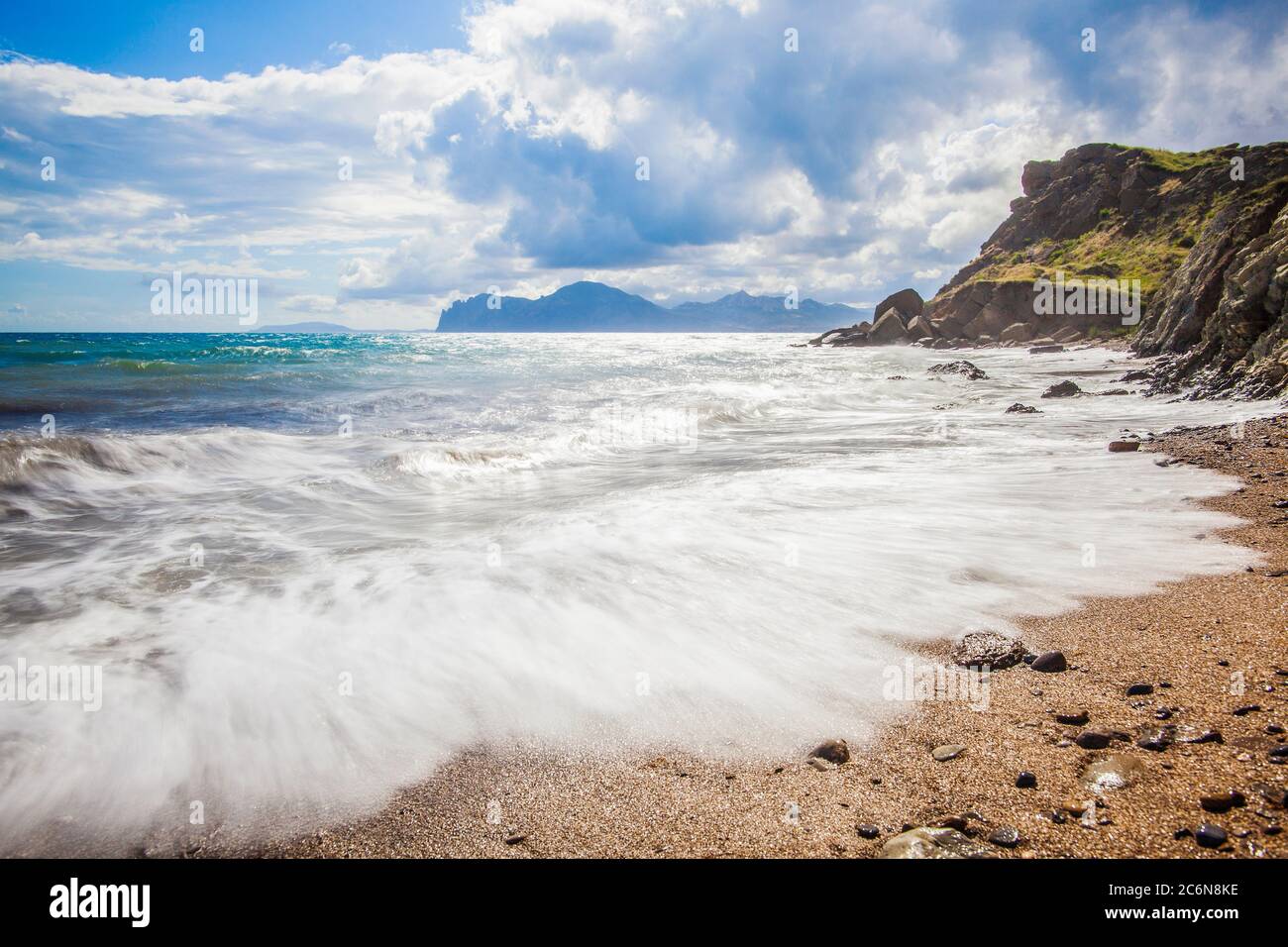 Sandy beach with mountains on background. Mountains are covered with ...