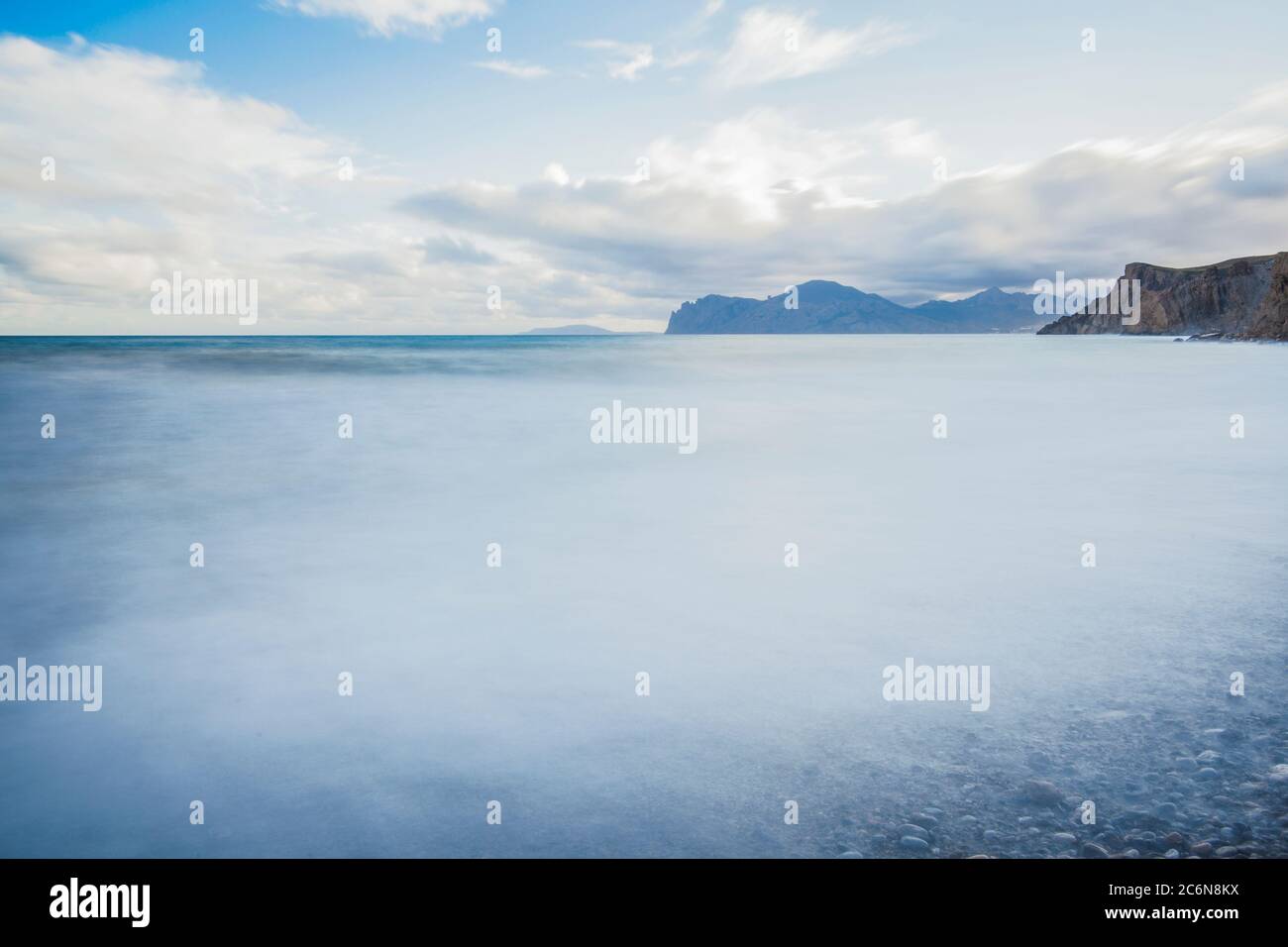 Sandy beach with mountains on background. Mountains are covered with ...