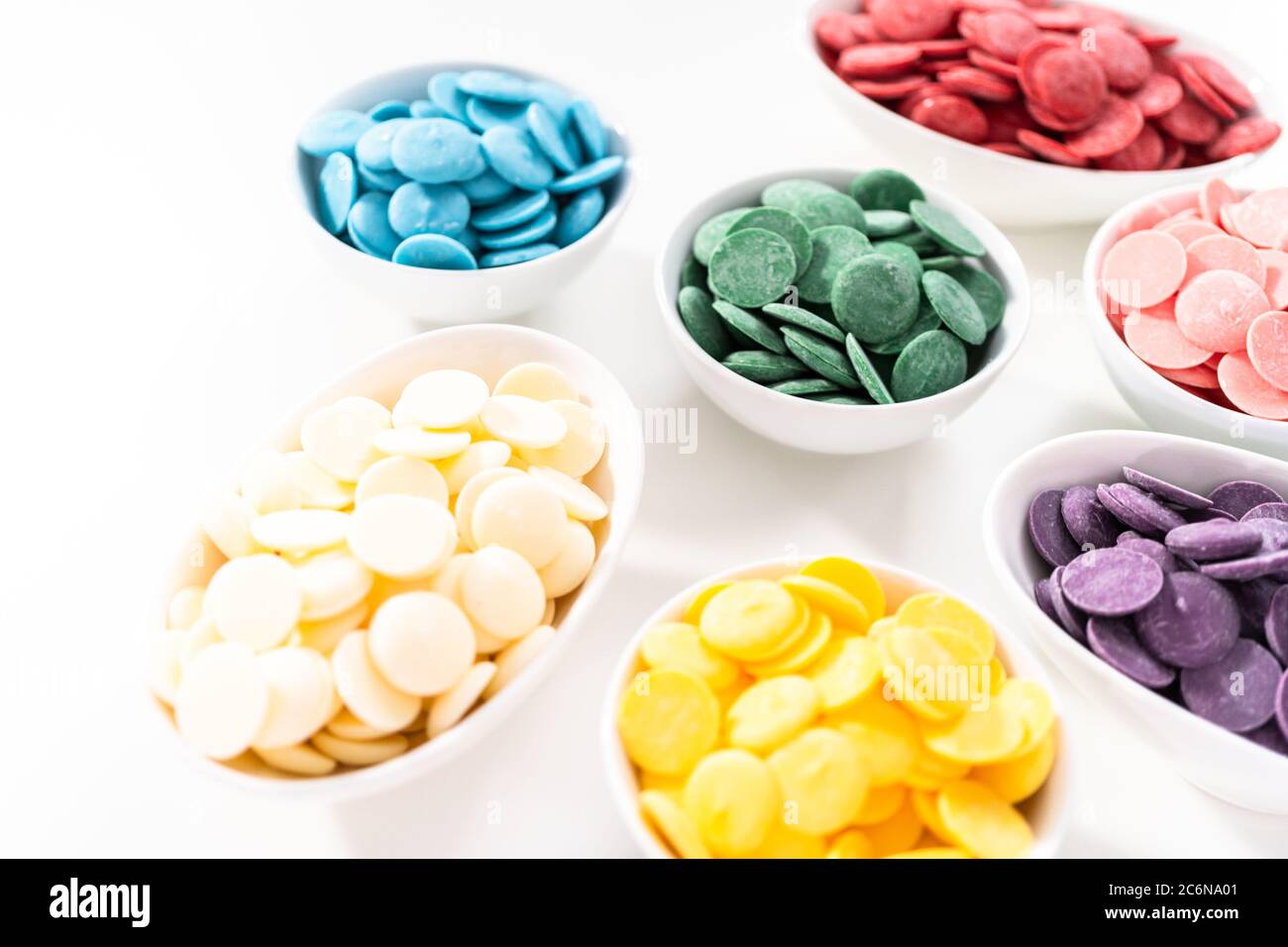 Rainbow colors of round chocolate chips in a white bowls for melting ...