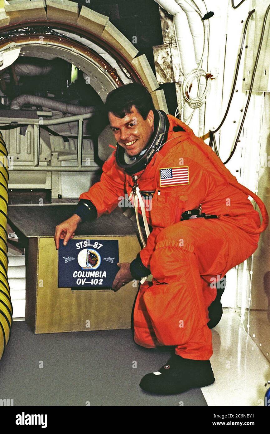 STS-87 Commander Kevin Kregel holds the crew patch in front of Columbia ...