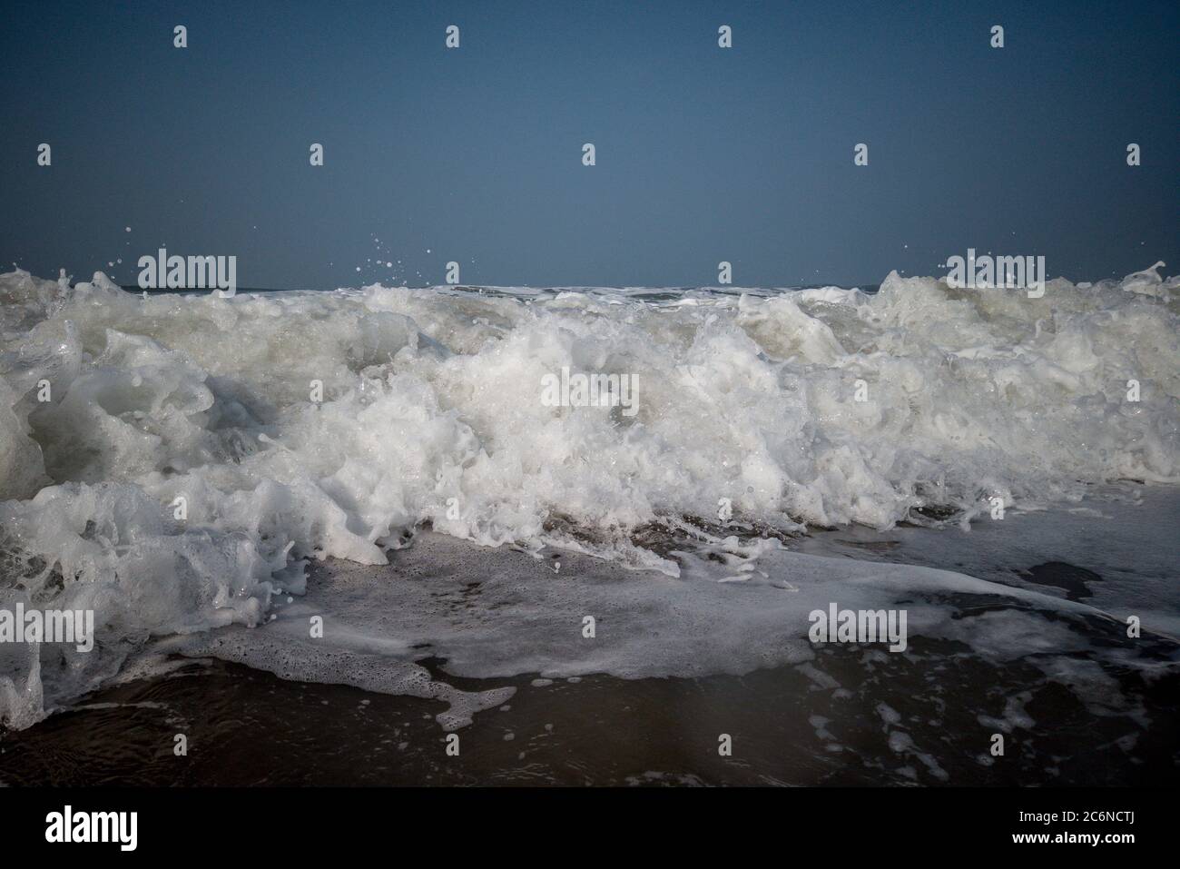 The low tide from the sandy beach. Ocean waves are splashing on the ...