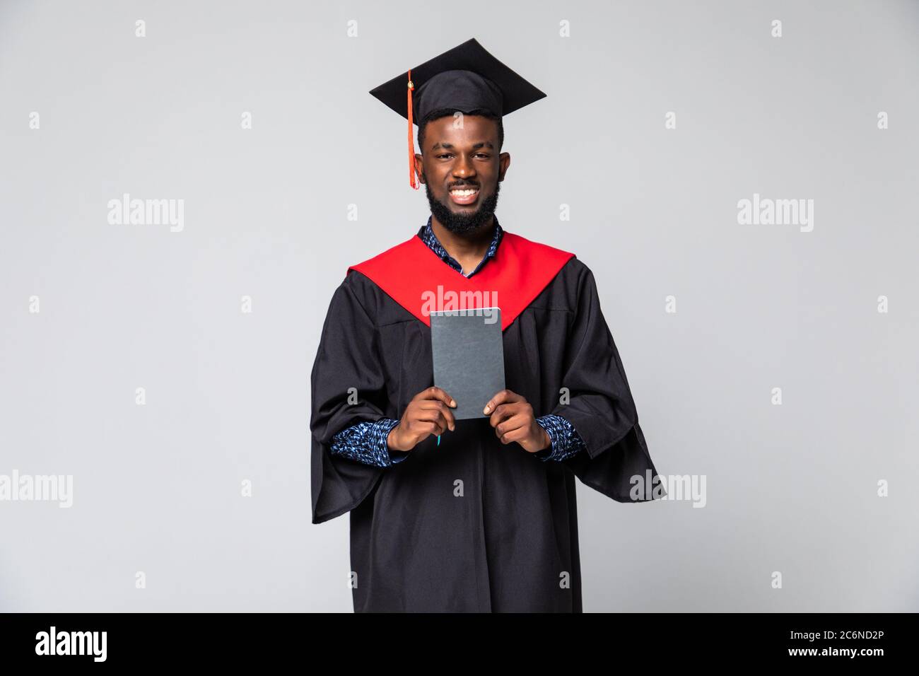 Male african american graduate in gown and cap isolated over white ...