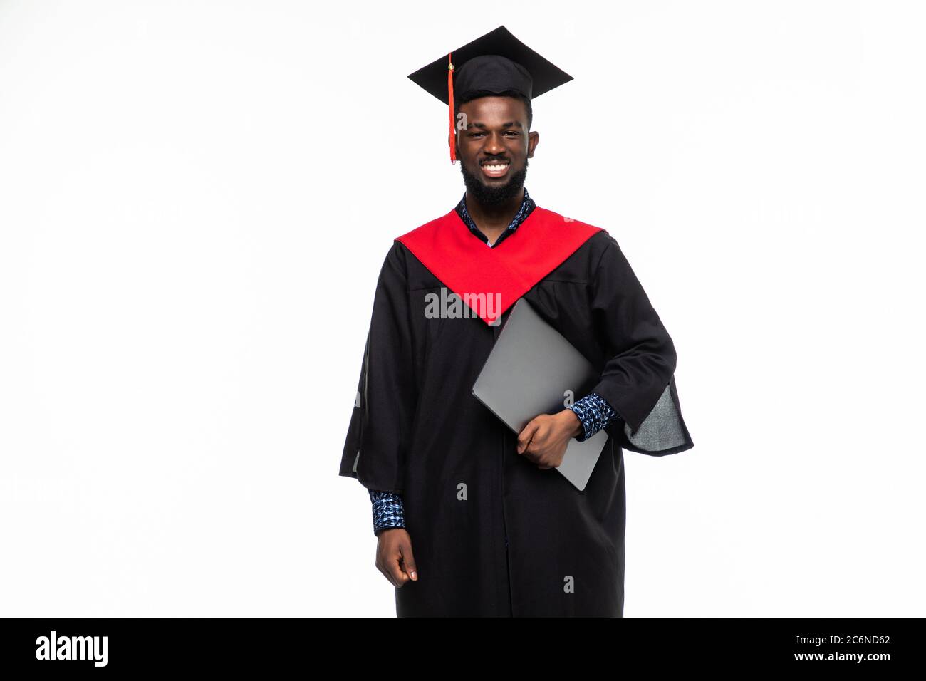 African man student in graduate robe with laptop over isolated white ...