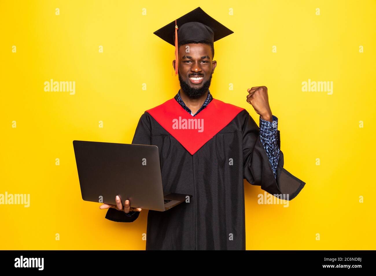 African American man college graduate holding laptop on yellow ...