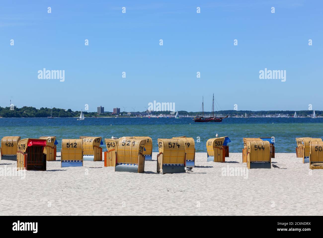 Sunny Beach Scene with Strandkorb Chairs and Sailboats. Leboe, Germany ...