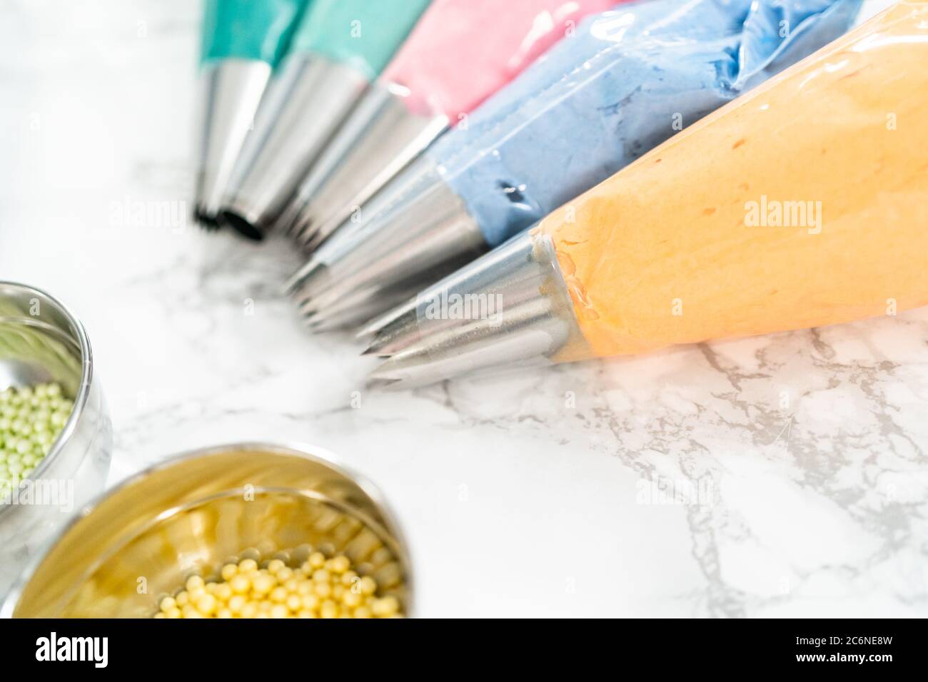 Piping bag with metal tips filled with colorful Italian buttercream ...