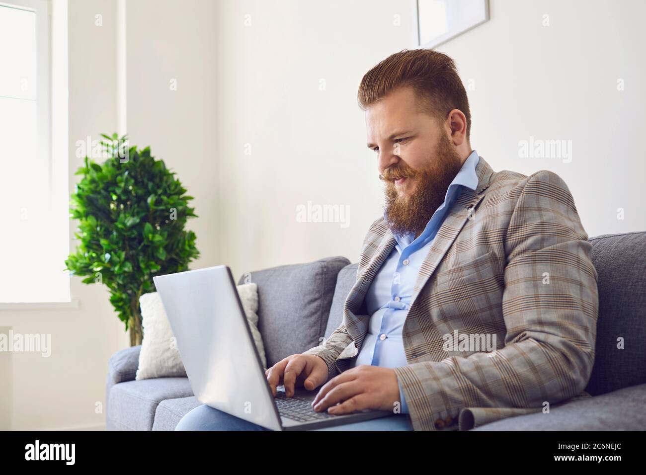 Work online at home office. Funny fat man works using a laptop in the ...