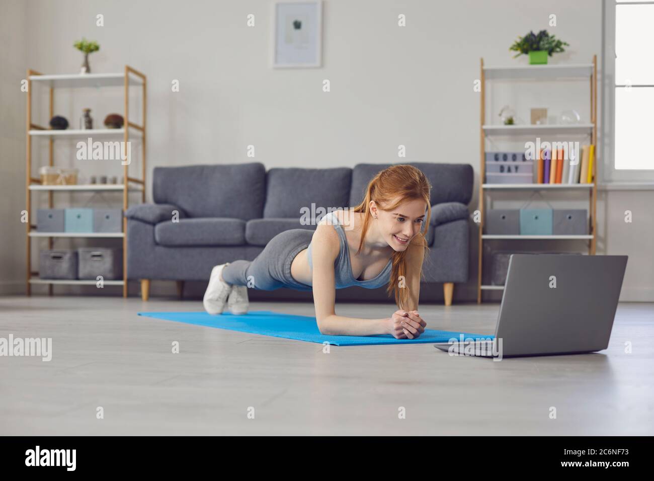 Online home sports. Pretty girl working out with laptop computer in ...