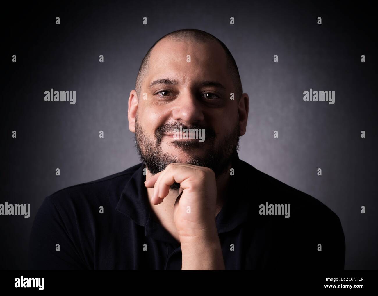 Close-up of young content man resting chin on fist, low key Stock Photo ...