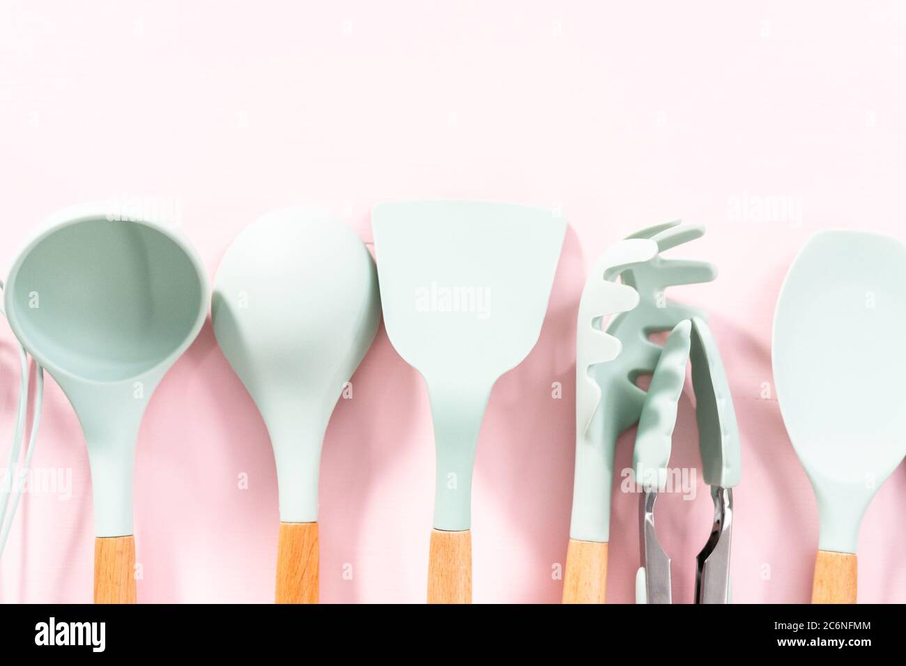 New blue silicone kitchen utensils with wooden handles on a pink ...