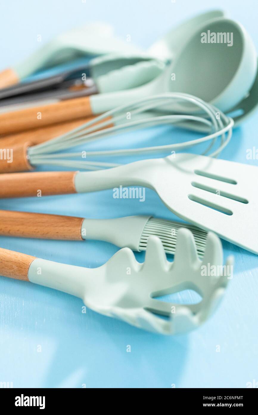 New blue silicone kitchen utensils with wooden handles on a blue ...