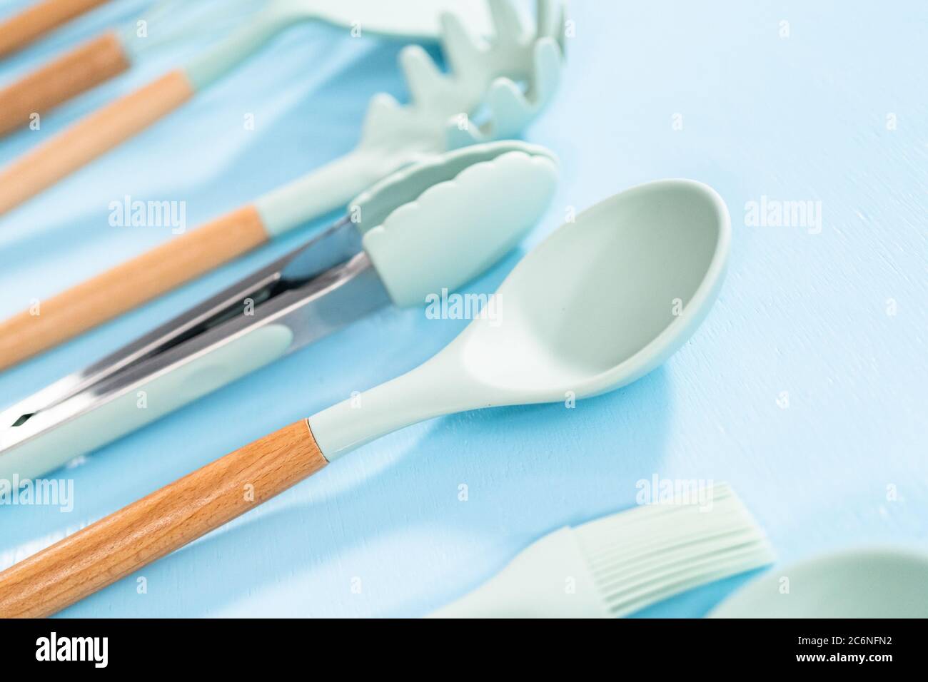 New blue silicone kitchen utensils with wooden handles on a blue ...