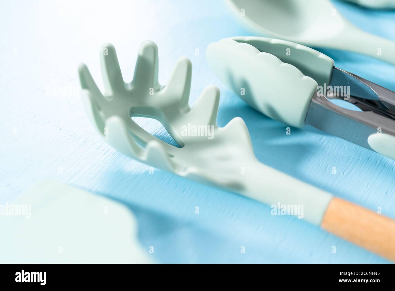 New blue silicone kitchen utensils with wooden handles on a blue ...