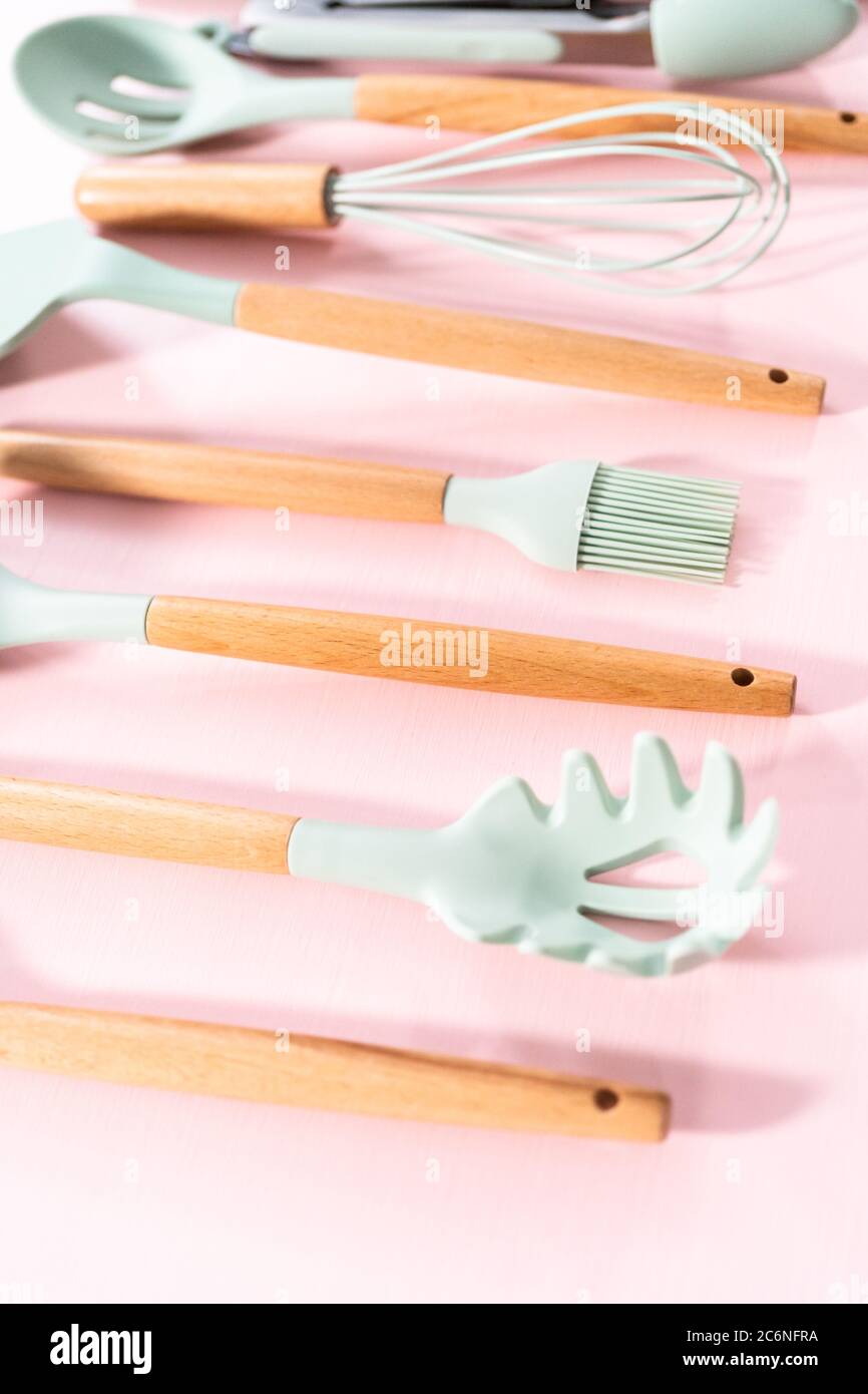 New blue silicone kitchen utensils with wooden handles on a pink ...
