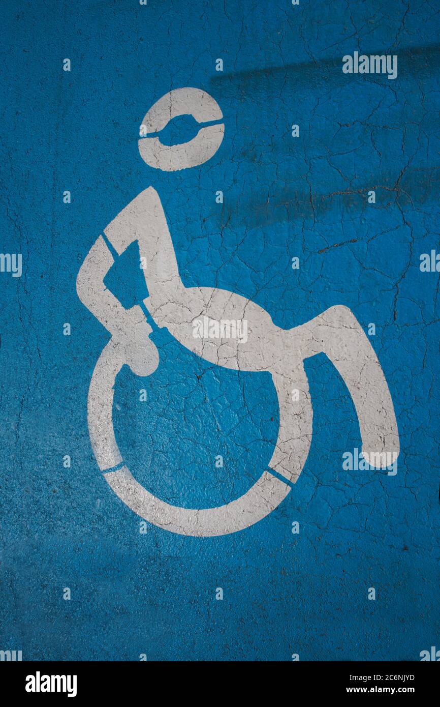 A road sign shaped like a wheelchair painted on the street with a blue ...