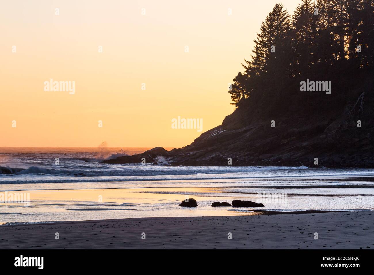 Orange skies and waves splashing on the rocks adding to an already ...