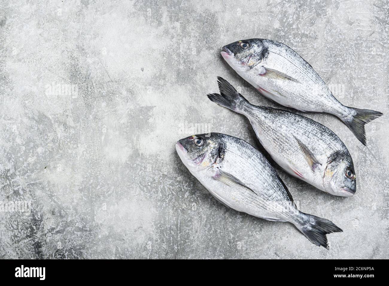 Whole dorado Sea bream fish with herbs for grill over textured grey ...