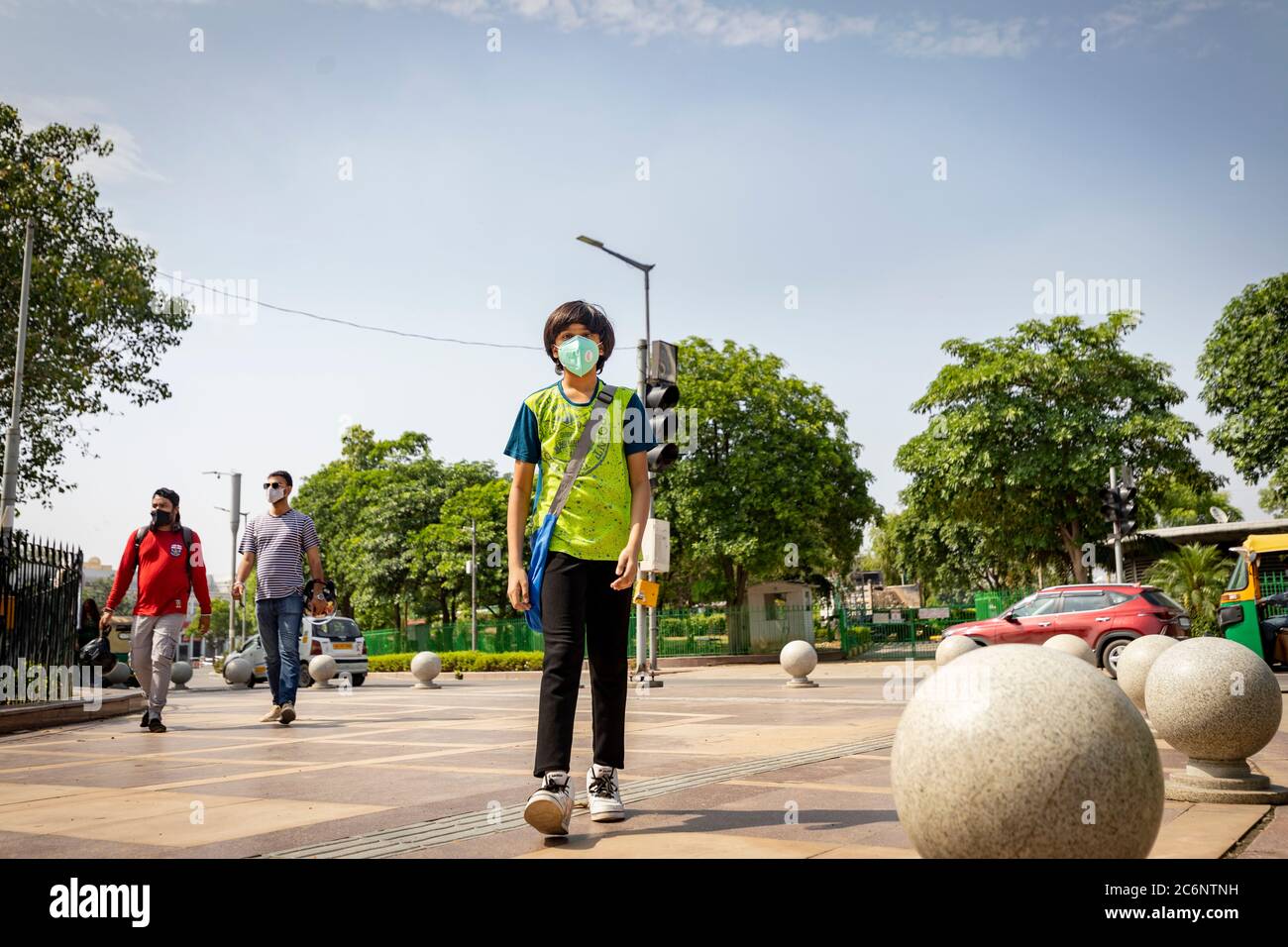 A young Indian boy wearing a corona protection mask walks on the ...