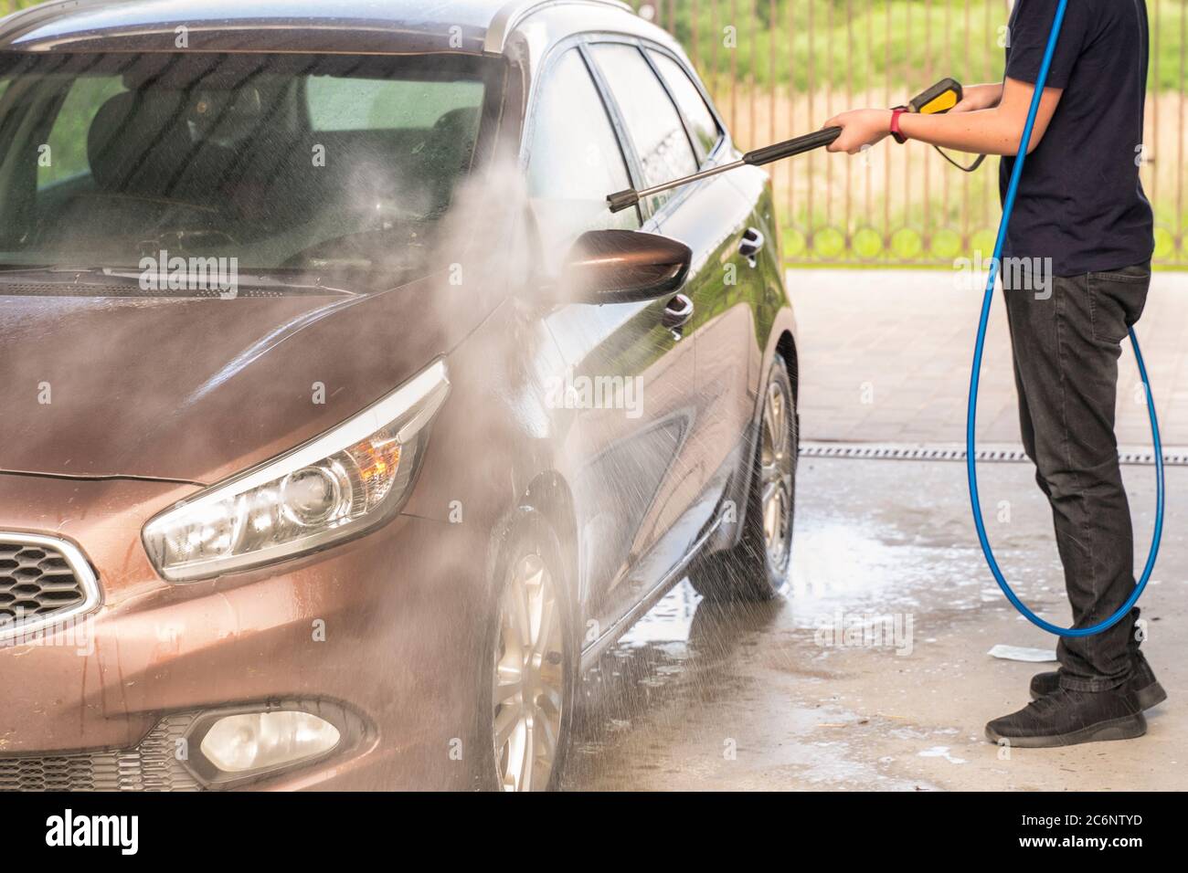 a man washes a brown car with a gun for washing high pressure cars ...