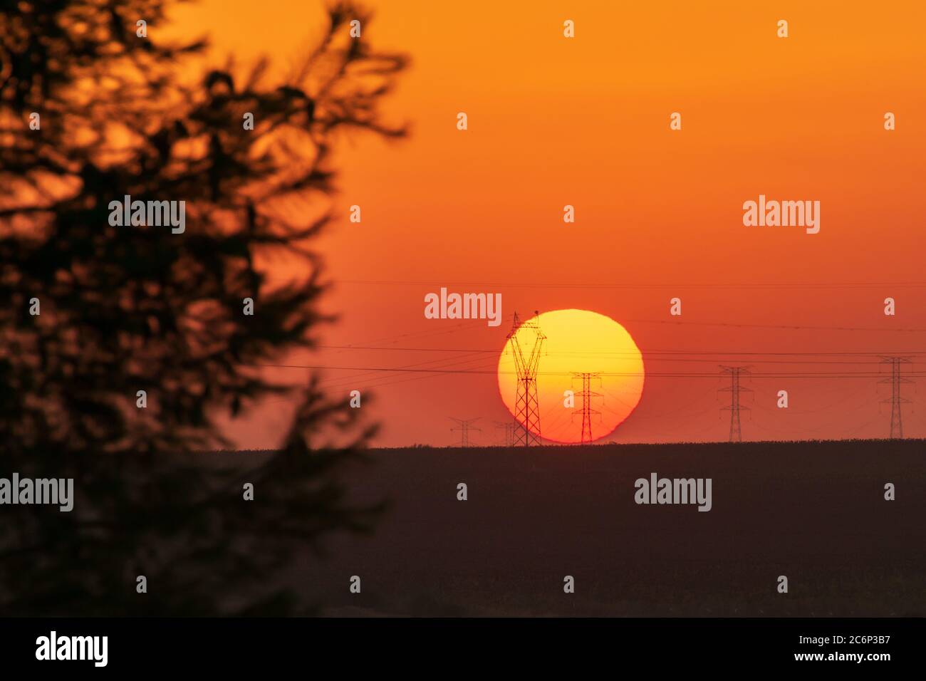Landscape of a sunset sun on the horizon line with high voltage pylons ...