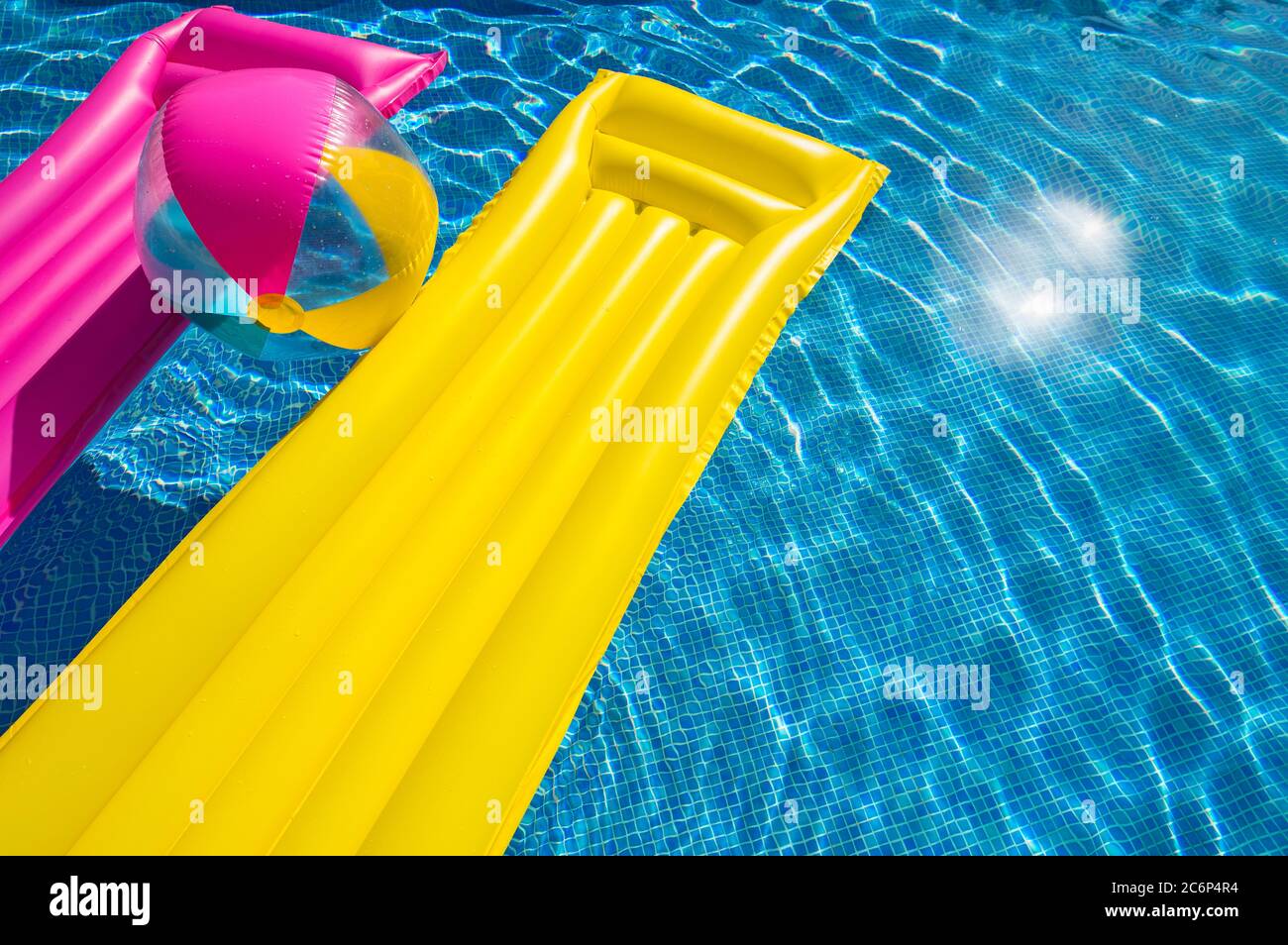 Yellow and pink inflatable air mattress with colorful beach ball ...