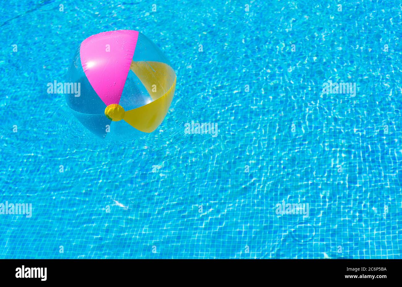 Inflatable colorful beach ball float on rippled blue swimming pool ...
