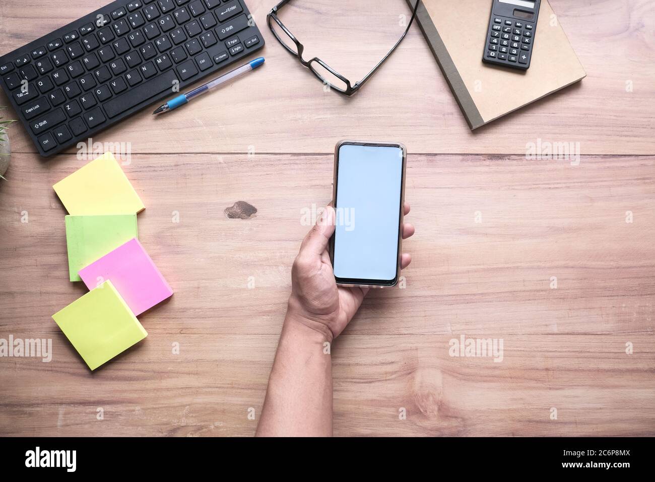 hand holding smart phone on desk with office suppliers Stock Photo - Alamy