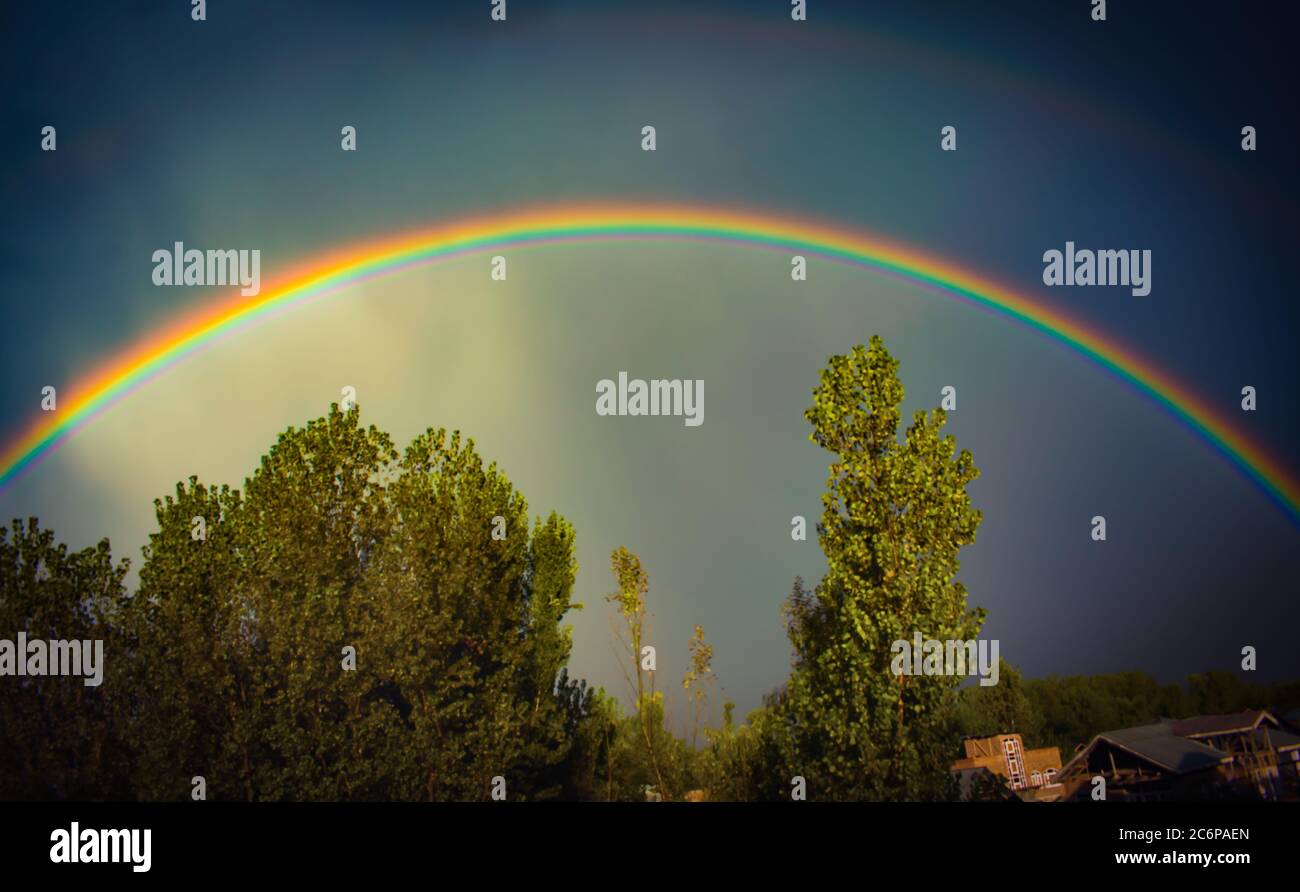 The bright rainbow in the sky. Rainbow over sky. Dramatic rainbow view ...