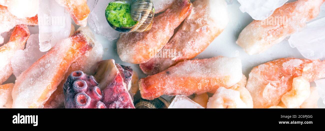 assortment of frozen seafood on ice cubes, shrimps, octopus, Babylonia ...