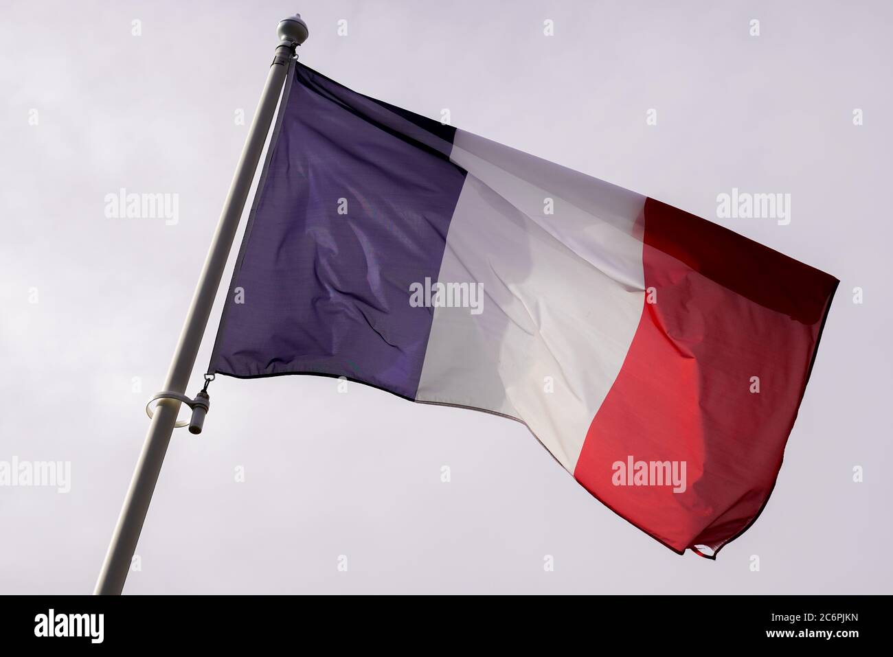 waving french flag against a grey cloud sky Stock Photo - Alamy
