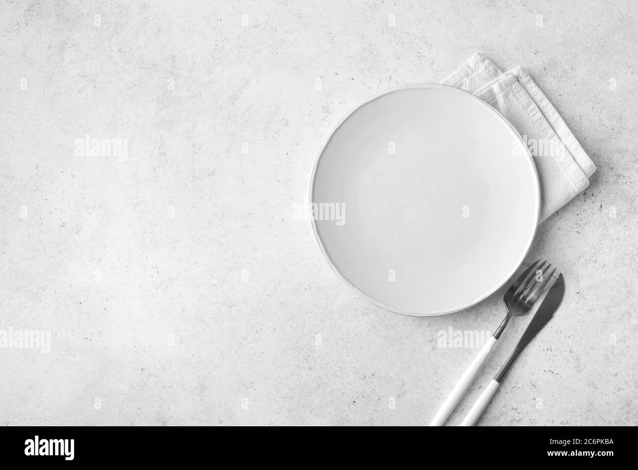 Empty white plate and cutlery, table setting on white stone table, top ...
