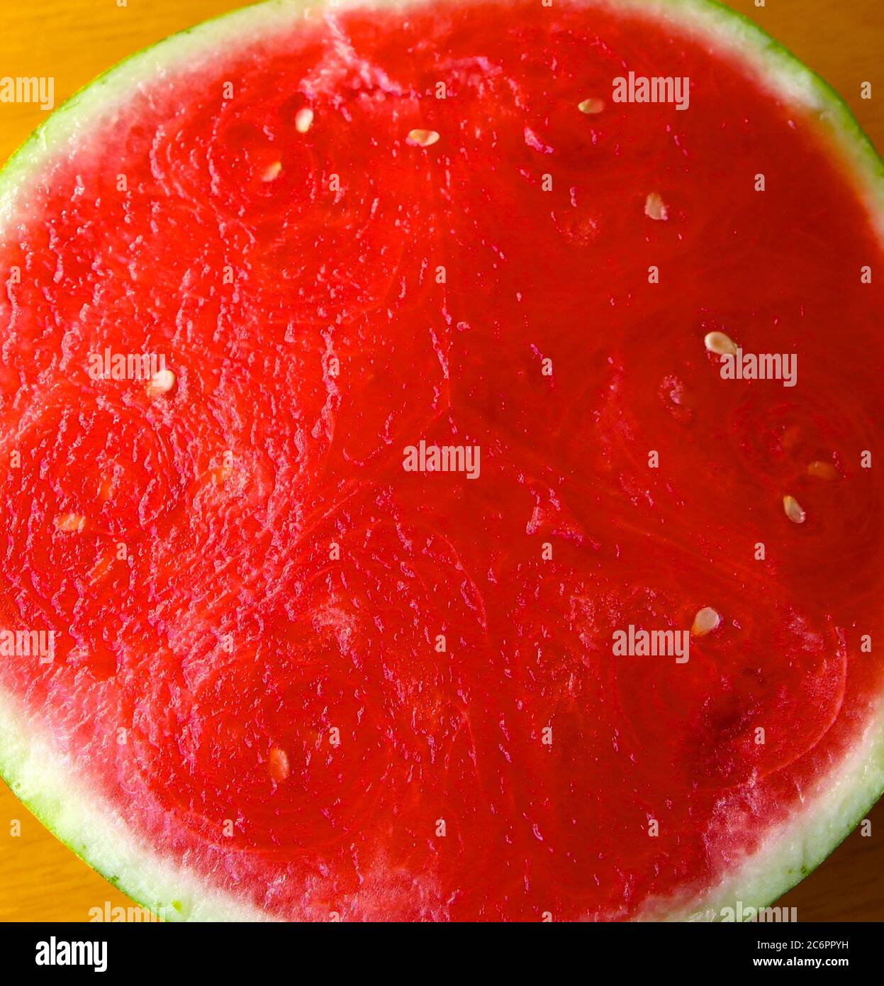 Fresh water melon cut in half showing the red flesh inside and yellow ...