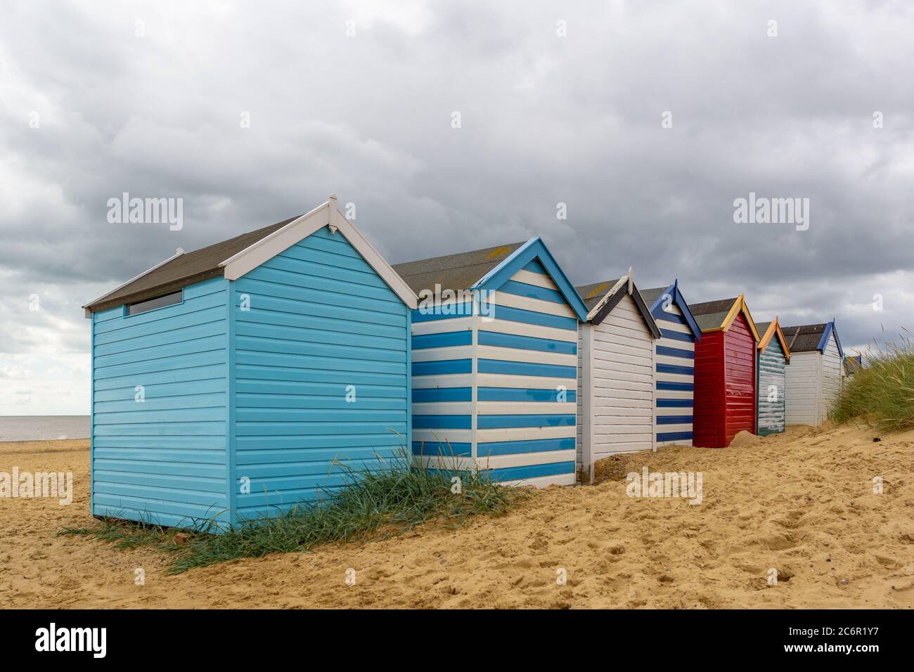 A line of beach huts on a sandy beach under a dramatic sky Stock Photo ...