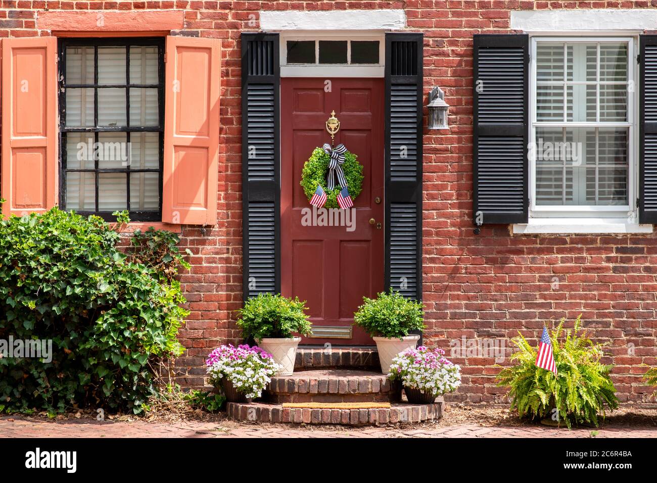 Old colonial style brick home is adorned with American flags for the ...