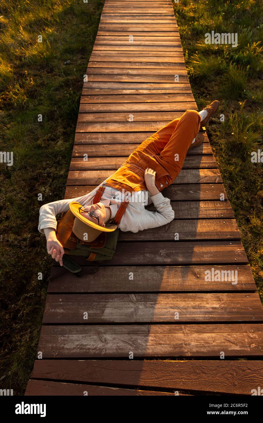 Woman naturalist in beige hat and orange overalls resting lying on a ...