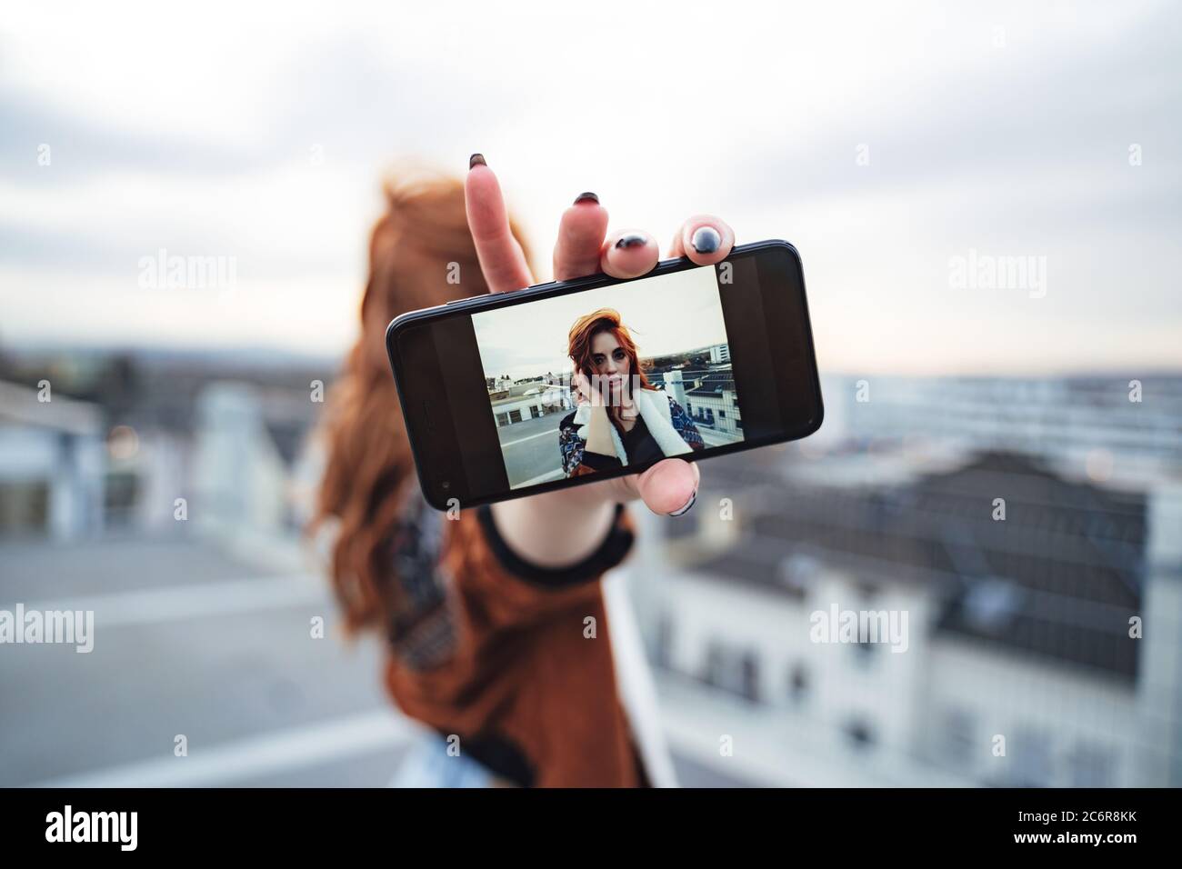 Young beautiful woman holding smart phone in outstretched hand. Phone ...