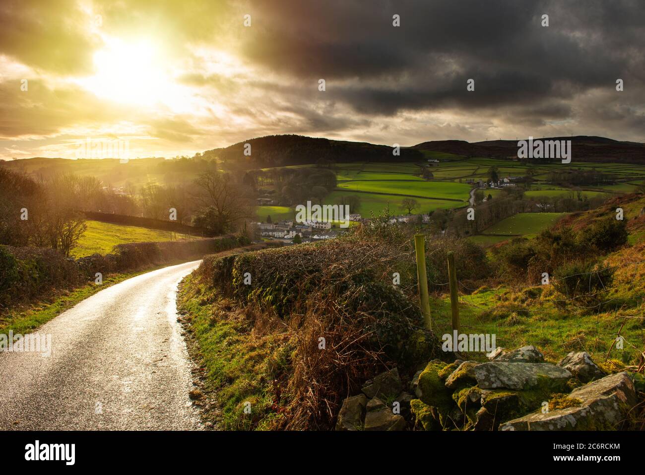 The sun breaks through the heavy rainclouds above Spark Bridge, Cumbria ...
