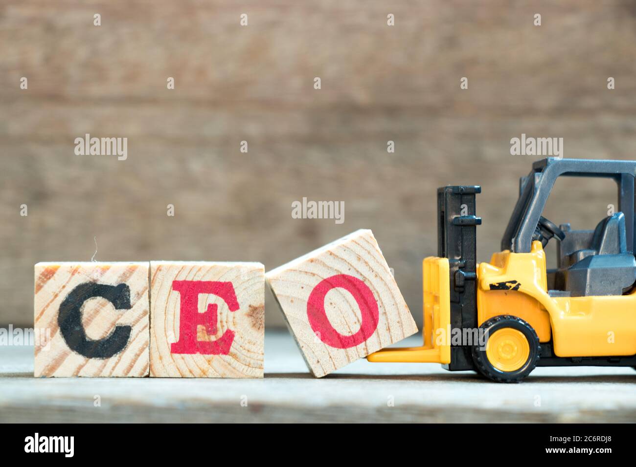 Yellow toy forklift hold letter block O to complete word CEO ...