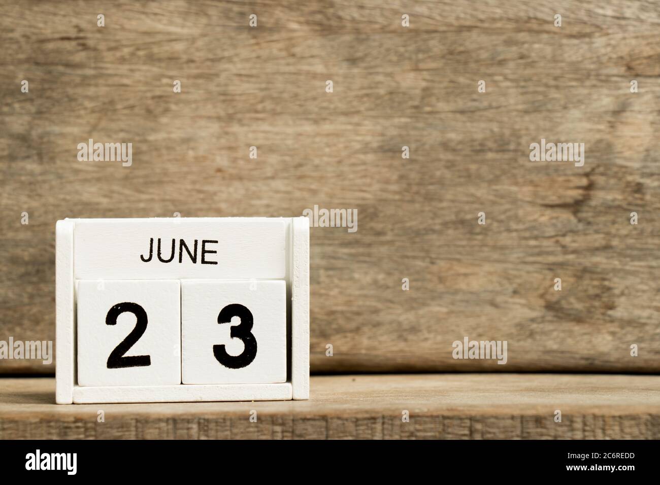 White block calendar present date 23 and month June on wood background ...