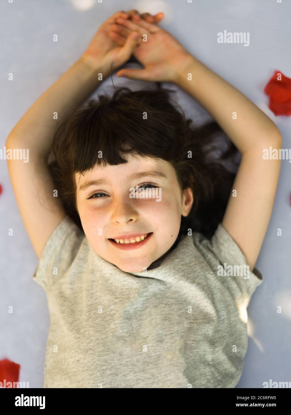 Close up portrait of smiling little girl while rose petals fall on her ... Close up portrait of smiling little girl while rose petals fall on her ...