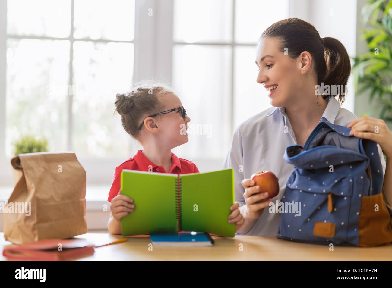 Happy family preparing for school. Little girl with mother putting ...