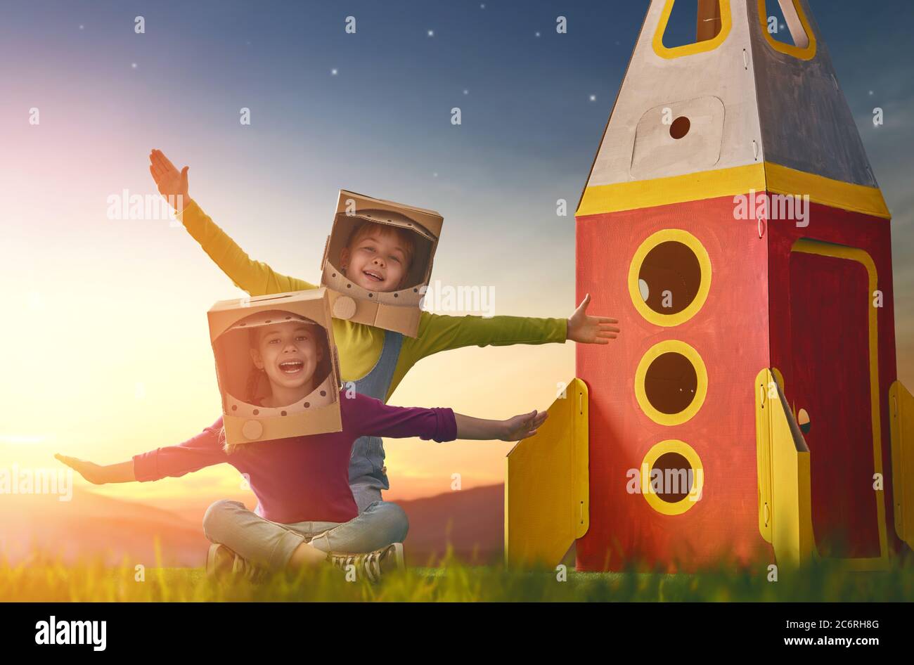 Children in astronauts costumes with toy rocket playing and dreaming of ...