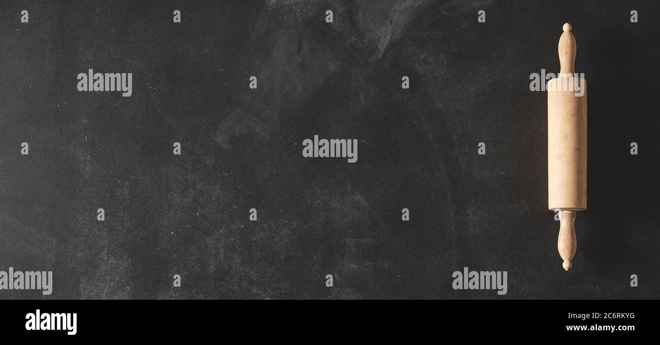 Clean simple wooden rolling pin on black slate in a panorama banner ...