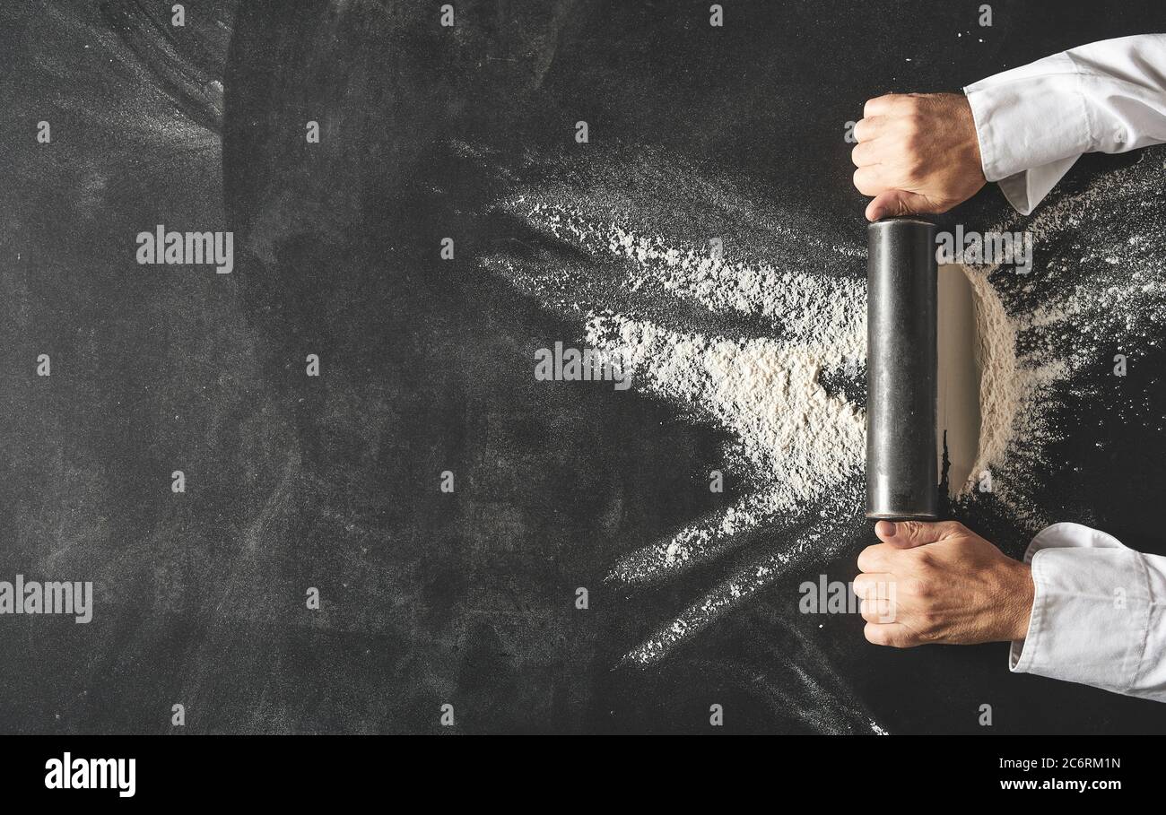 Chef rolling out flour with a rolling pin in an overhead view of the ...